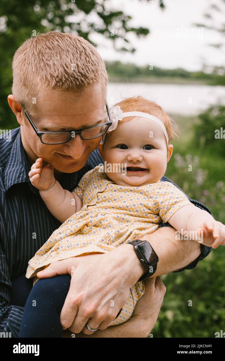 Dad holds and hugs smiling and happy baby red head daughter Stock Photo ...