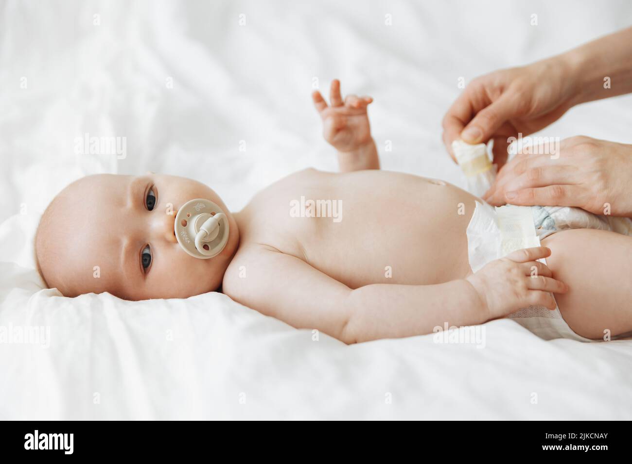Side view portrait of a happy mother changing her baby's diaper on the ...
