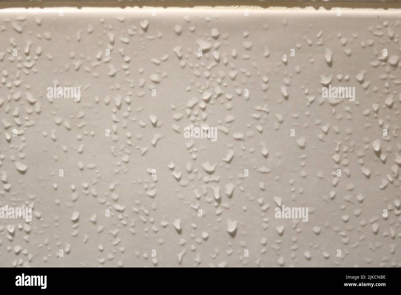 Small water droplets running down wet beige ceramic bathroom tiles ...
