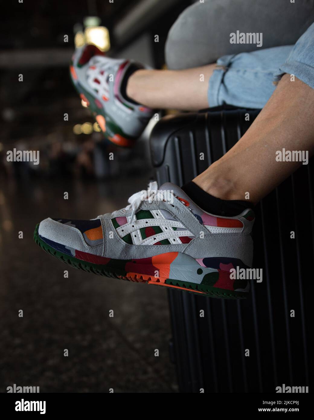 The left foot of a person with colorful sneaker and the right one on ...