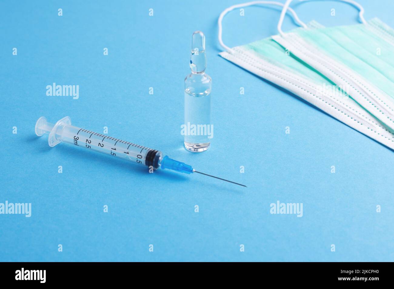 Vial medication and sharp needle on blue background. Medical treatment ...
