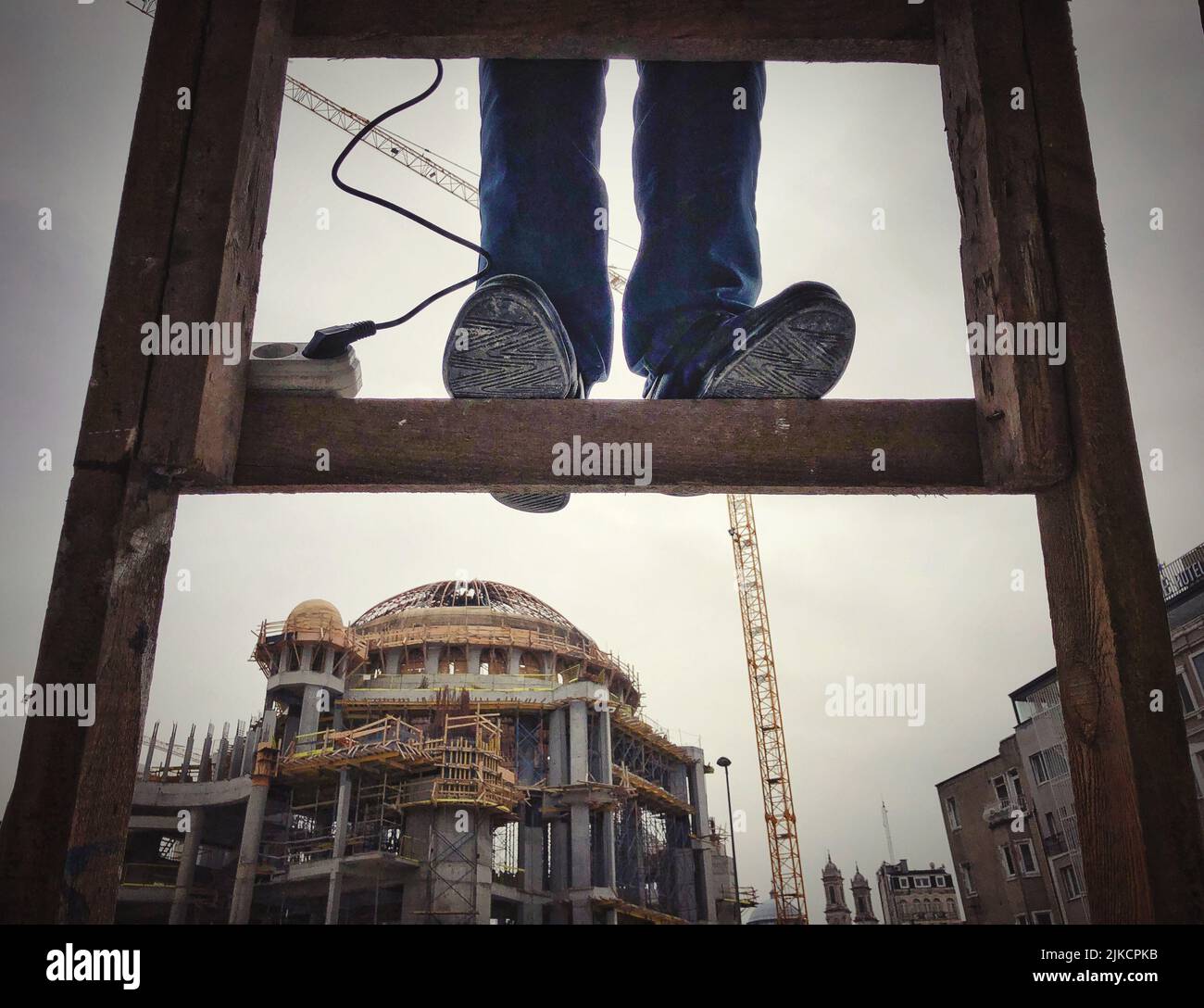 A low-angle shot of a person's legs standing on the step of a ladder ...