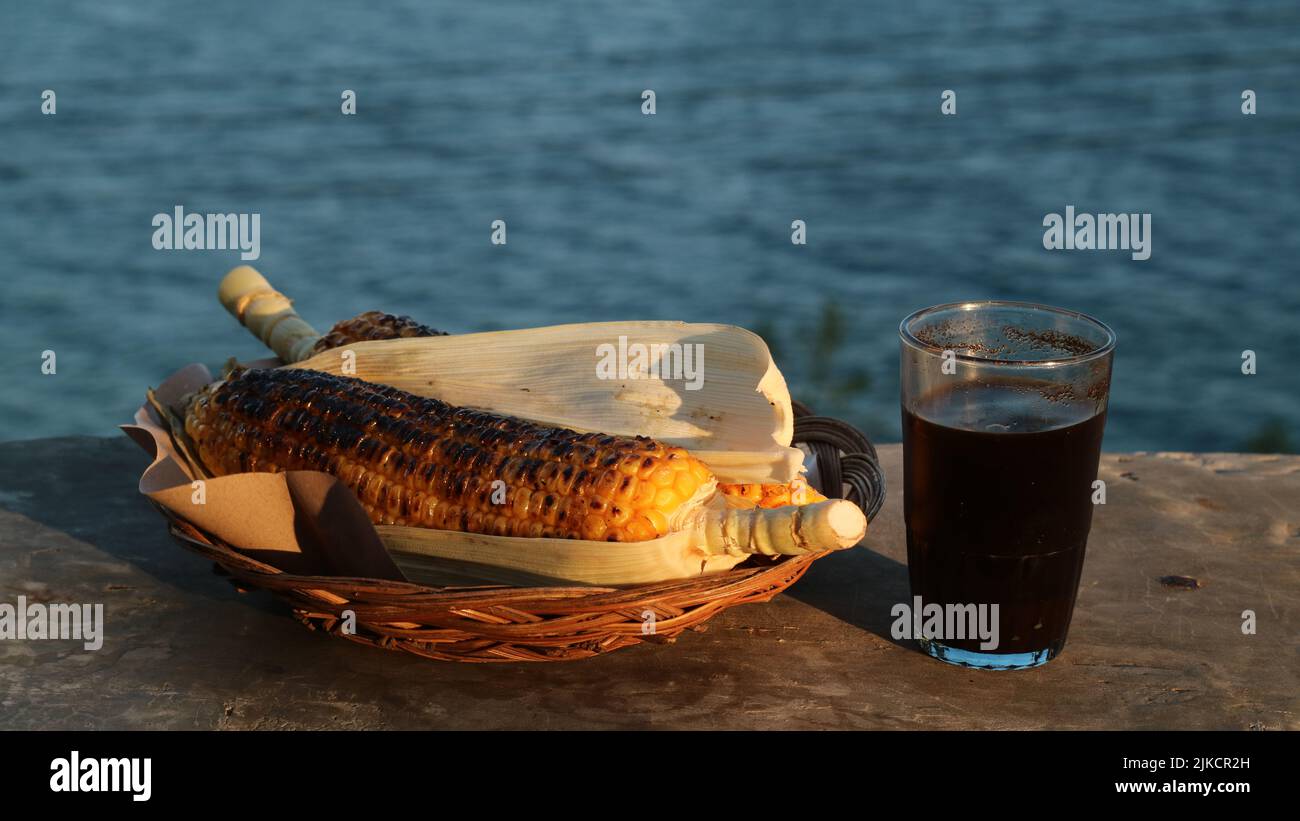a cup of black coffee and two roasted corn Stock Photo - Alamy