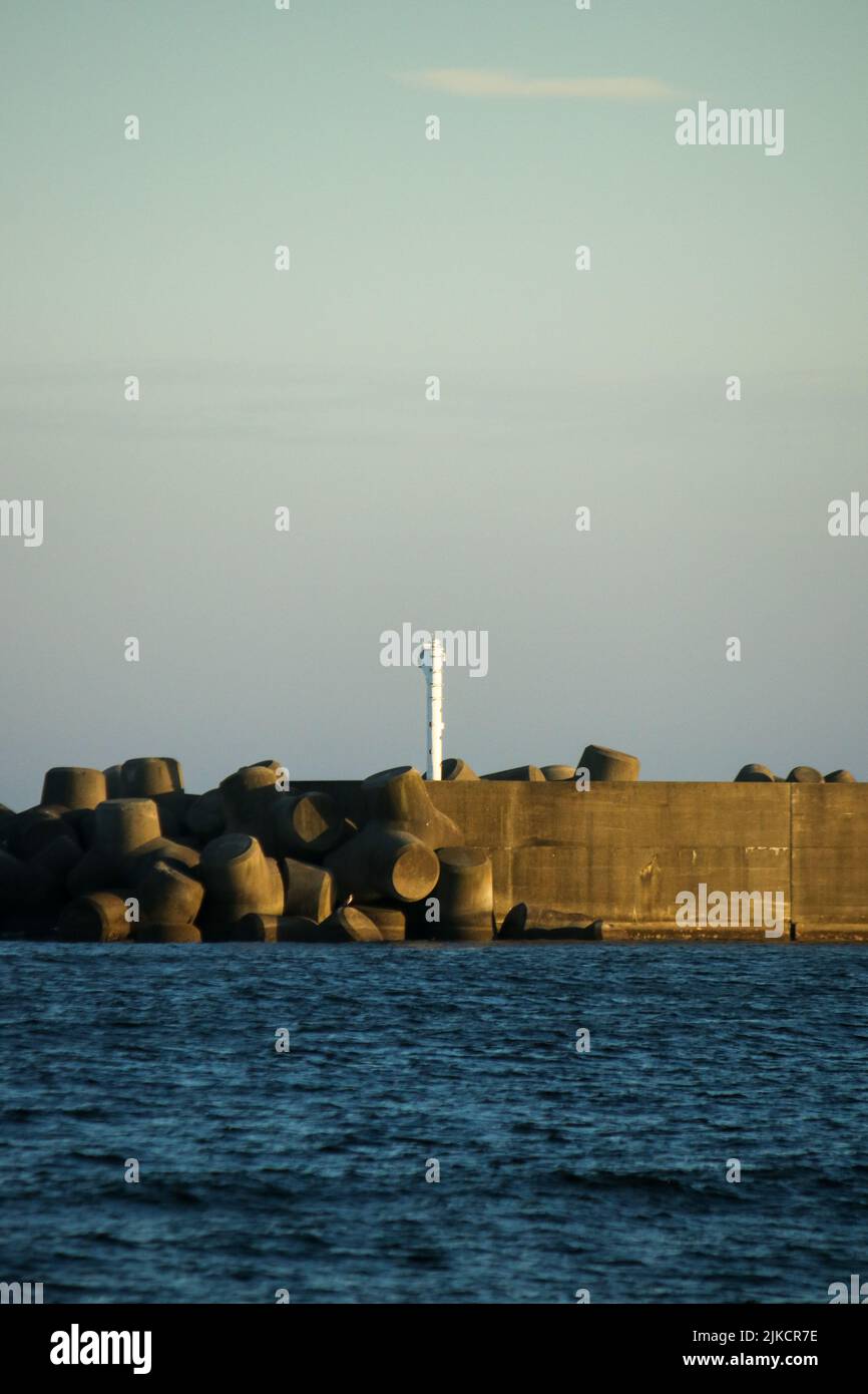 A vertical of a lighthouse post on tetrapod concrete sea defenses Stock ...