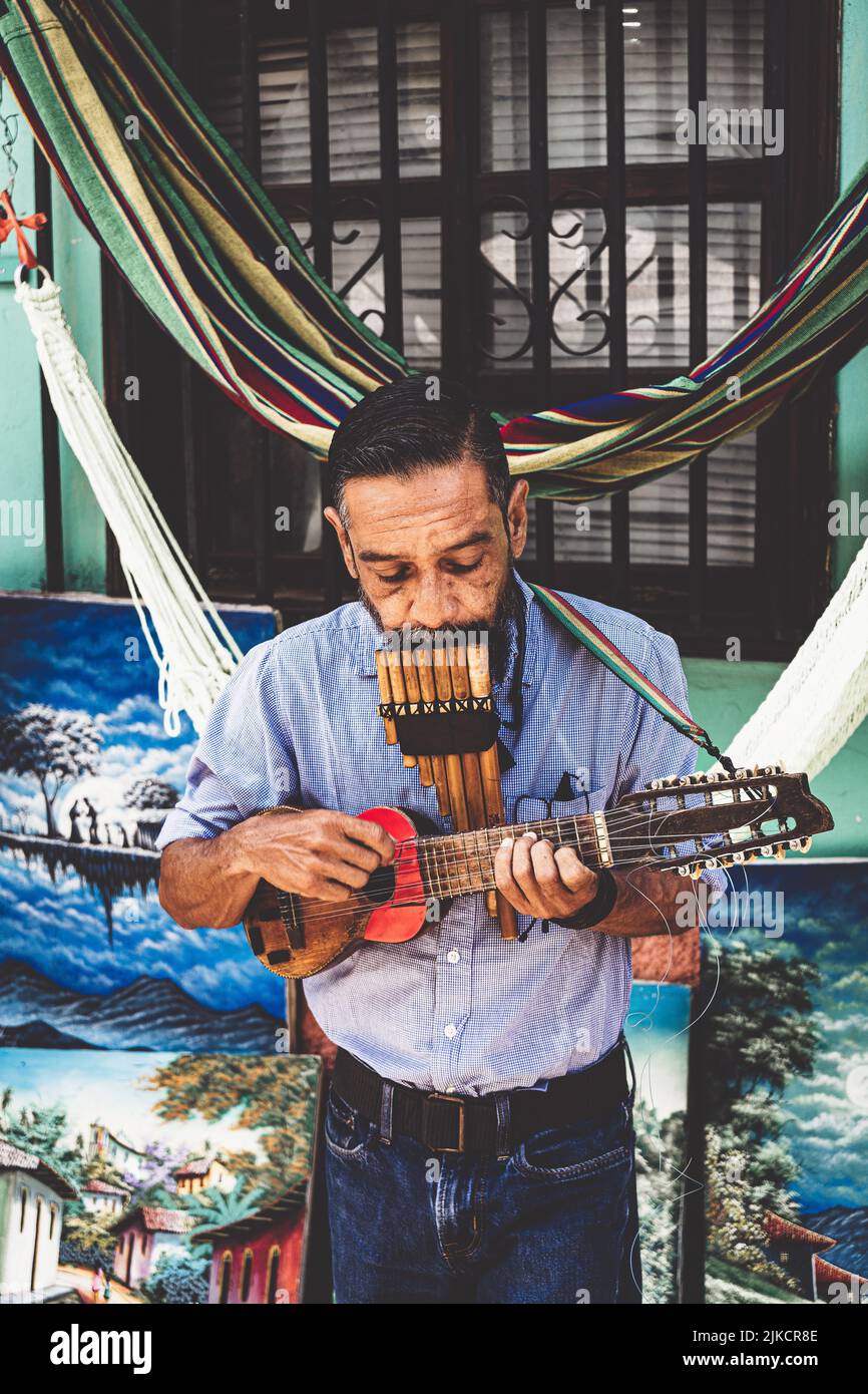 A vertical shot of a male musician playing with a small guitar and ...