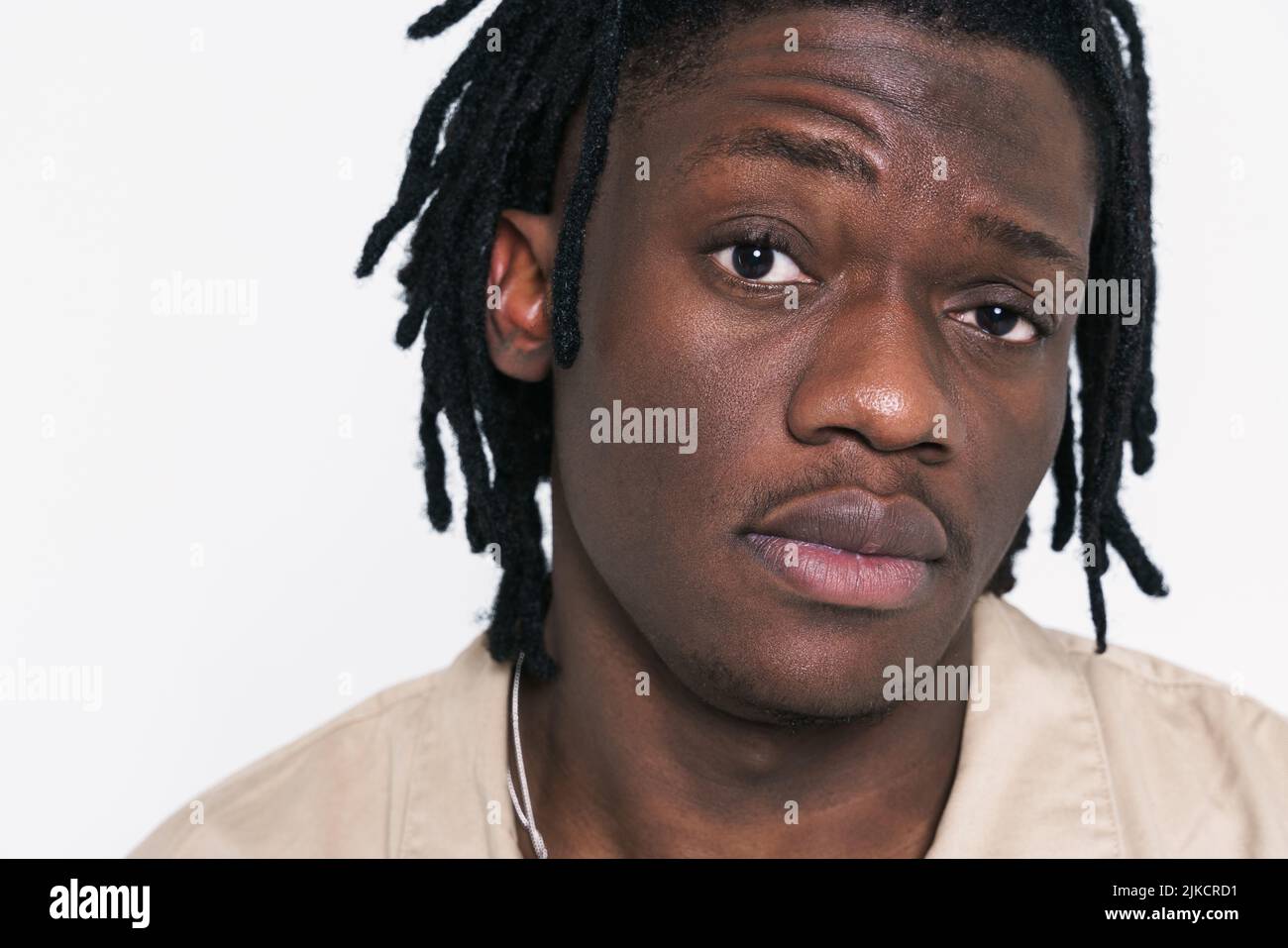 Young black man with dreadlocks posing and looking at camera isolated ...