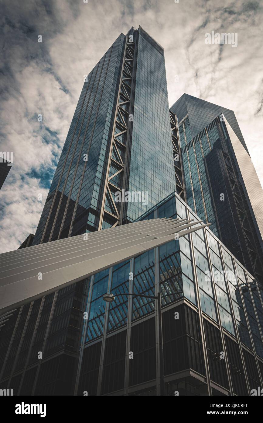 A vertical low angle of a modern glass building against sky background ...