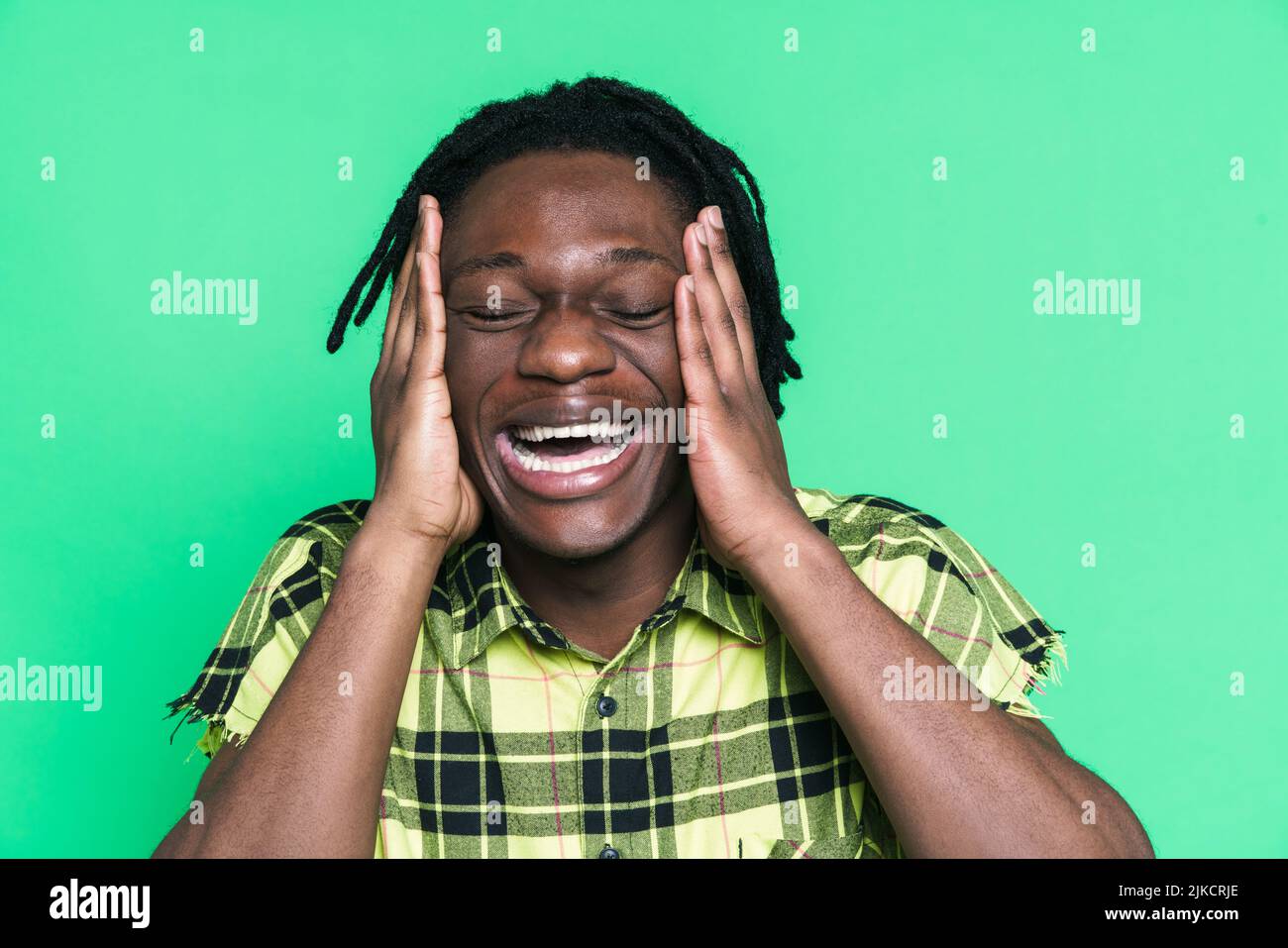 Young black man with dreadlocks laughing while holding his head ...