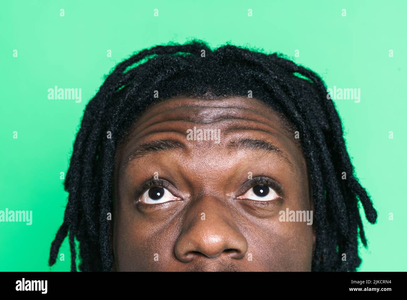 Young black perplexed man posing and looking upward isolated over green ...