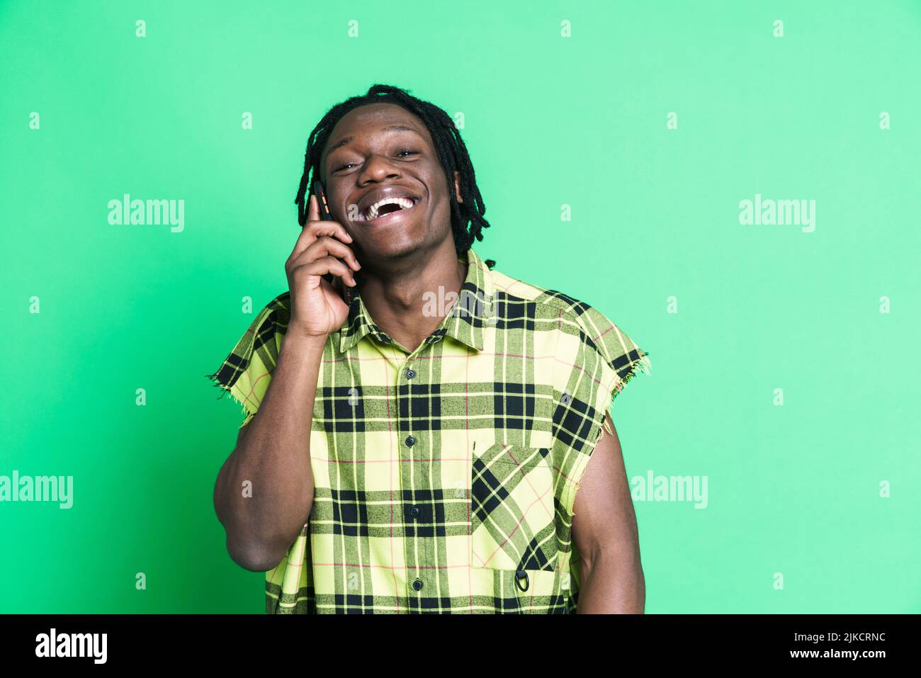 Young black man with dreadlocks talking on mobile phone isolated over ...