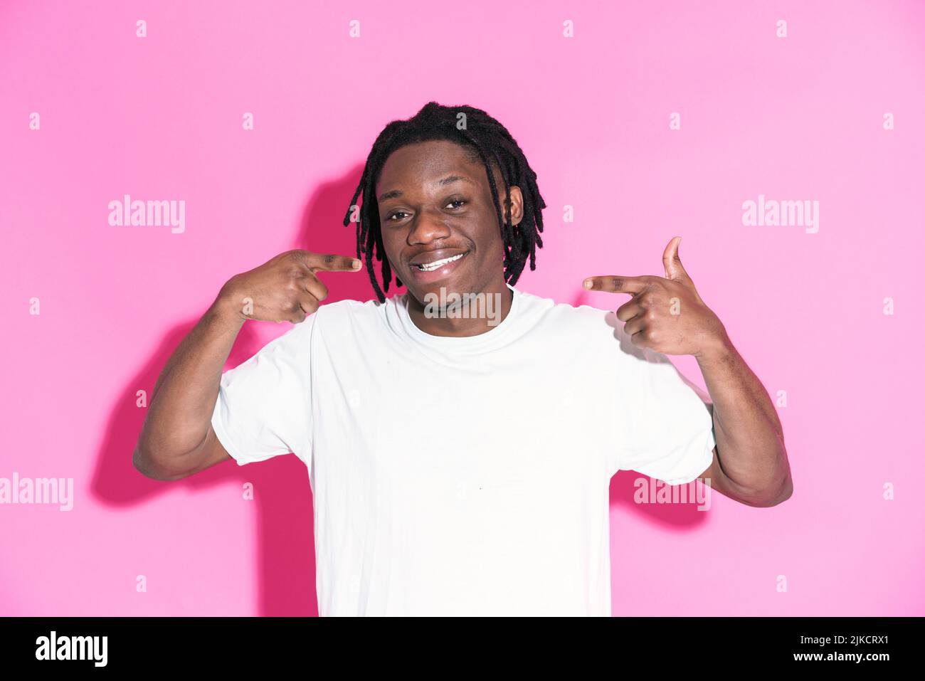 Young black man with dreadlocks pointing fingers at his smile isolated ...
