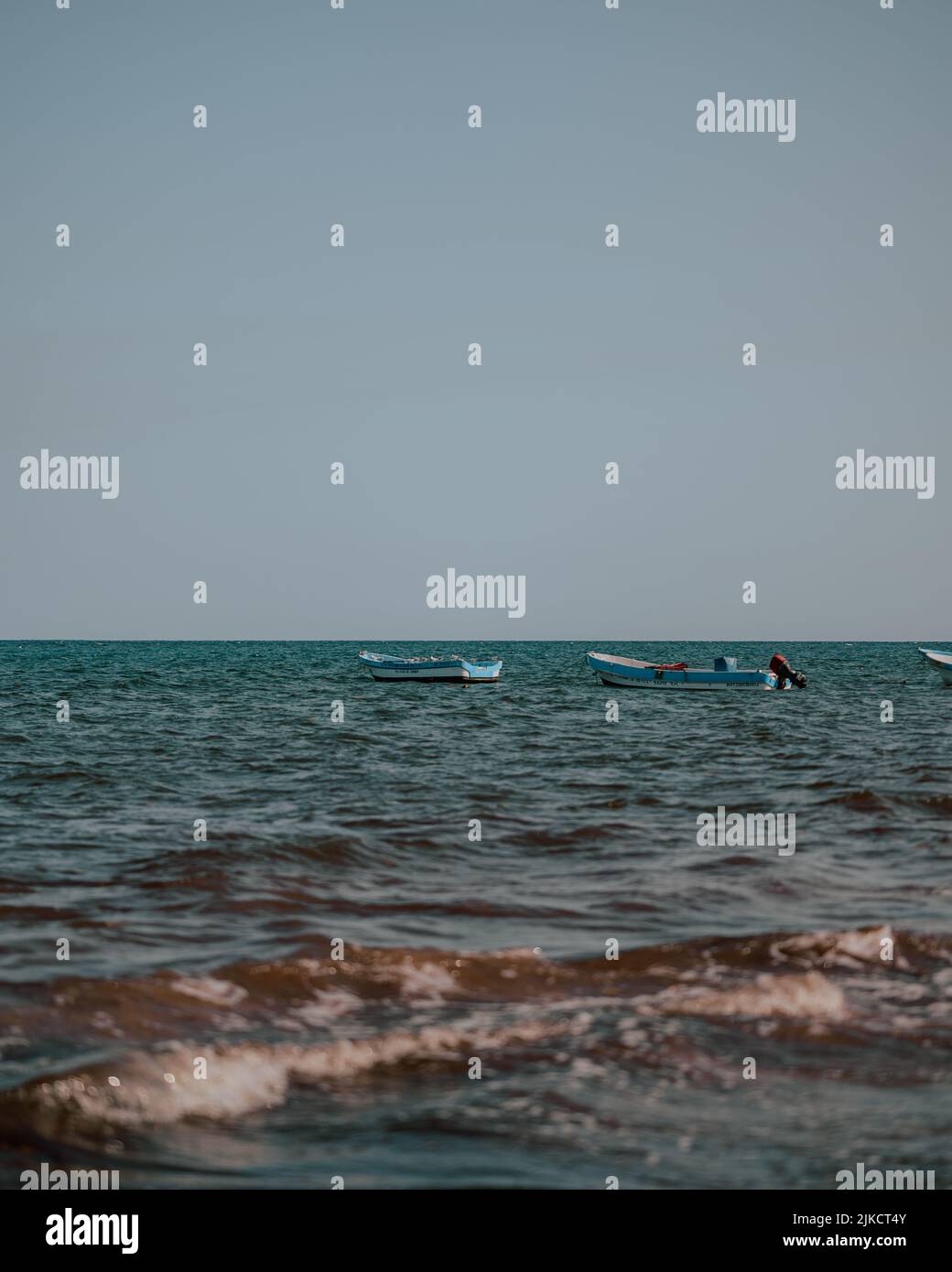 A vertical shot of the waves of the ocean washing the beach of Tulum ...