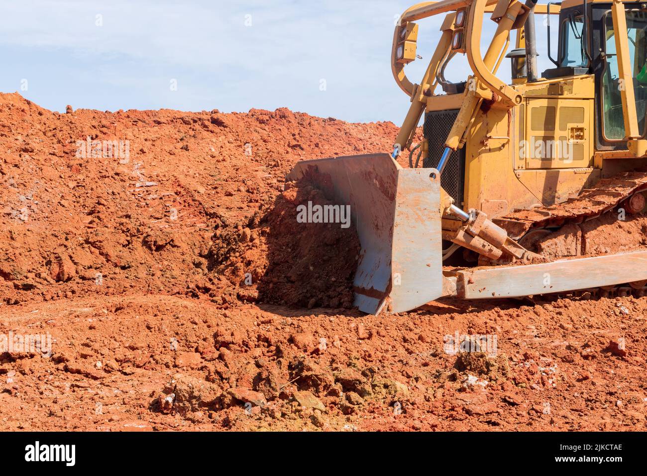 A bulldozer is working with earth soil while doing landscaping on a ...