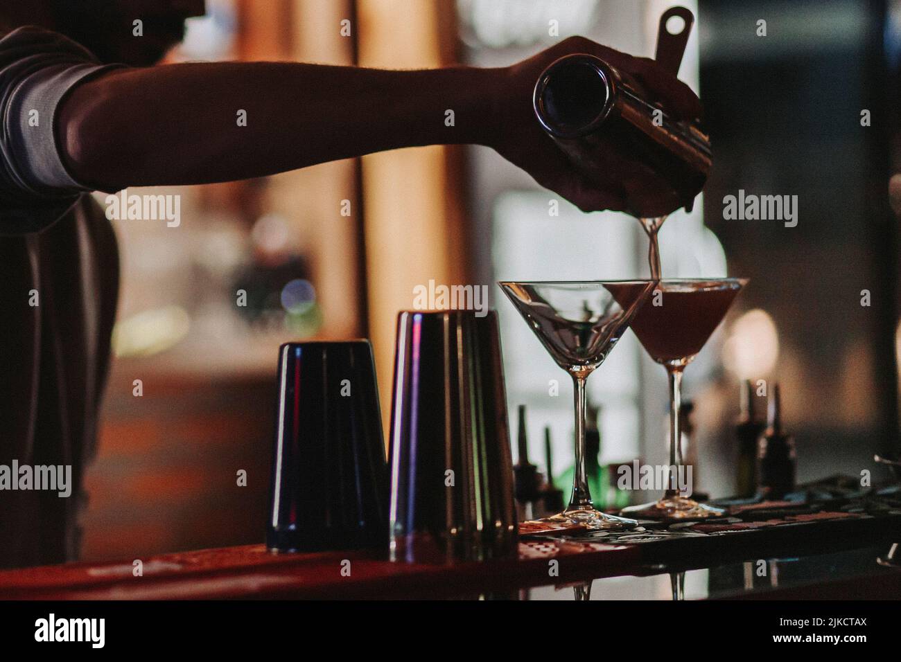 A bartender's hand pouring drinks into the glasses on bar counter Stock Photo - Alamy