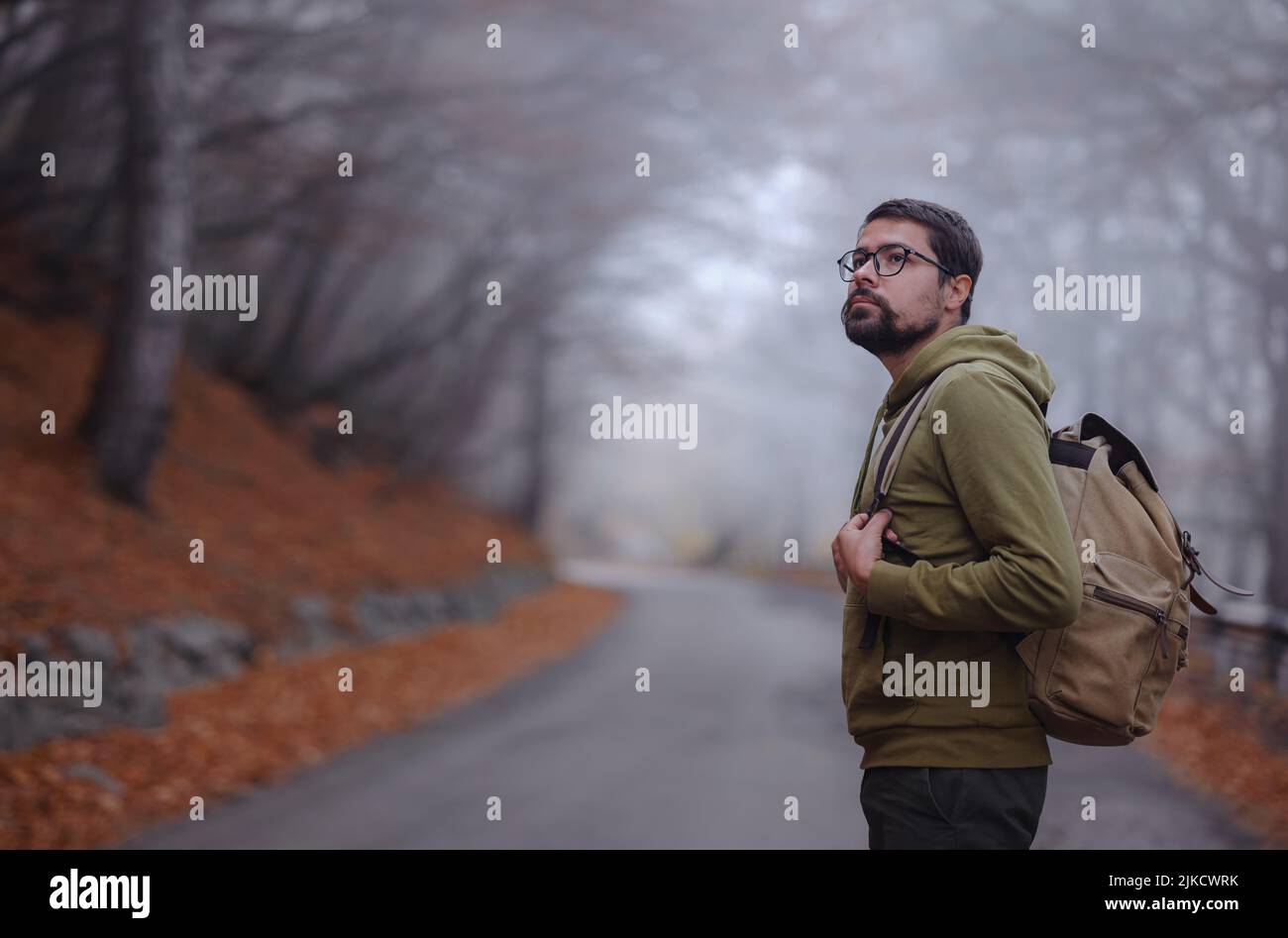 Young handsome man posing in autumn forest on road. young hipster guy ...