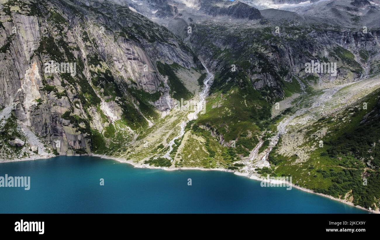 An aerial view of a blue dam on the shore of mountains in Guttannen ...