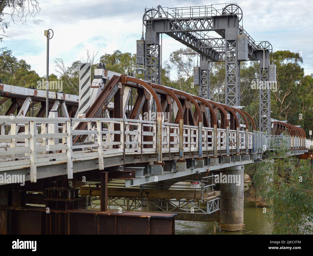 The old metal bridge above the river surrounded by green vegetation ...
