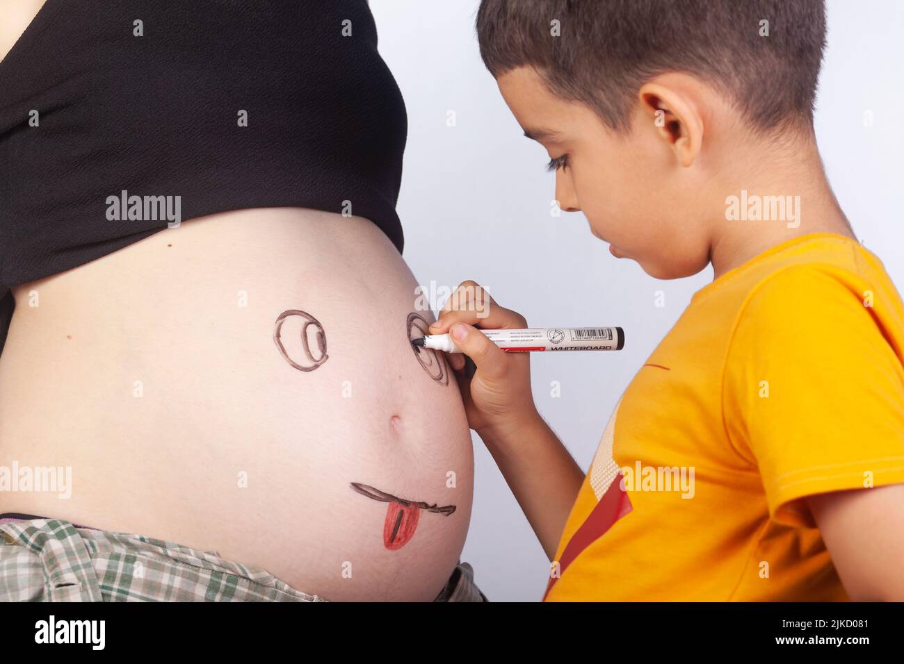 A closeup of a young boy drawing face on a pregnant belly Stock Photo ...