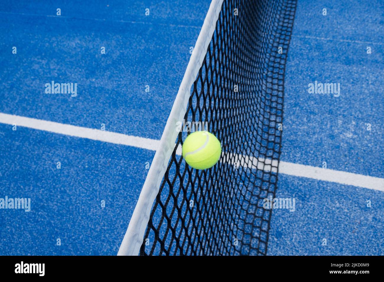 a ball in the air over the net of a paddle tennis court, racket sports ...