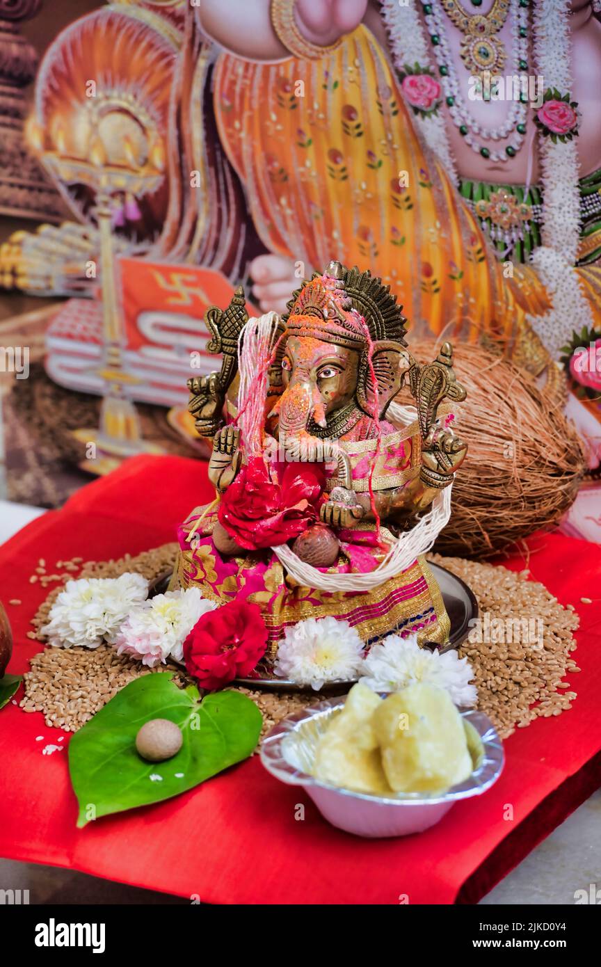 A vertical shot of a bronze statue of Hindu god Ganesha on a table with ...