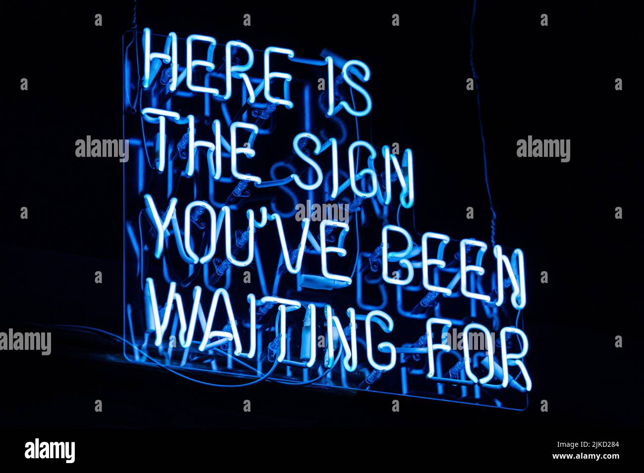 An illuminated blue motivation "here is the sign you've been waiting ...
