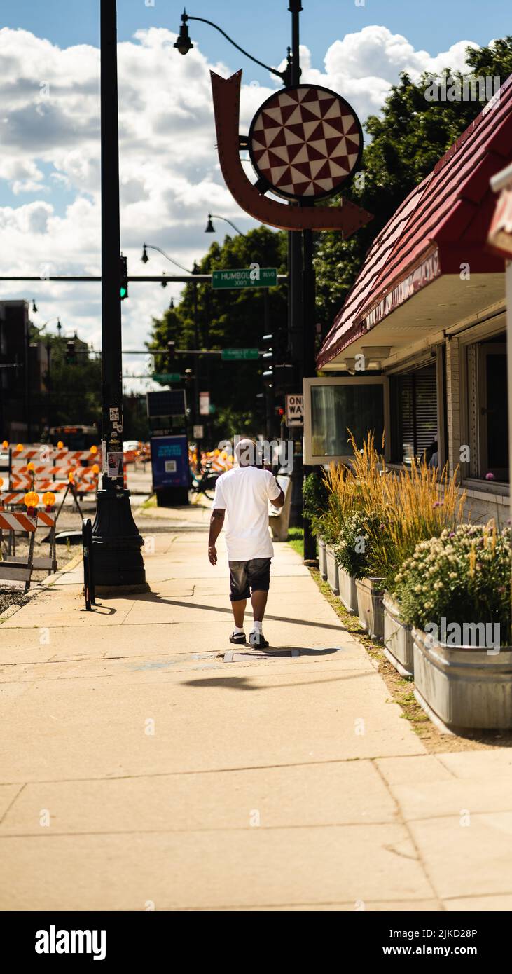 A rear view of an African-American male talking on phone while walking ...
