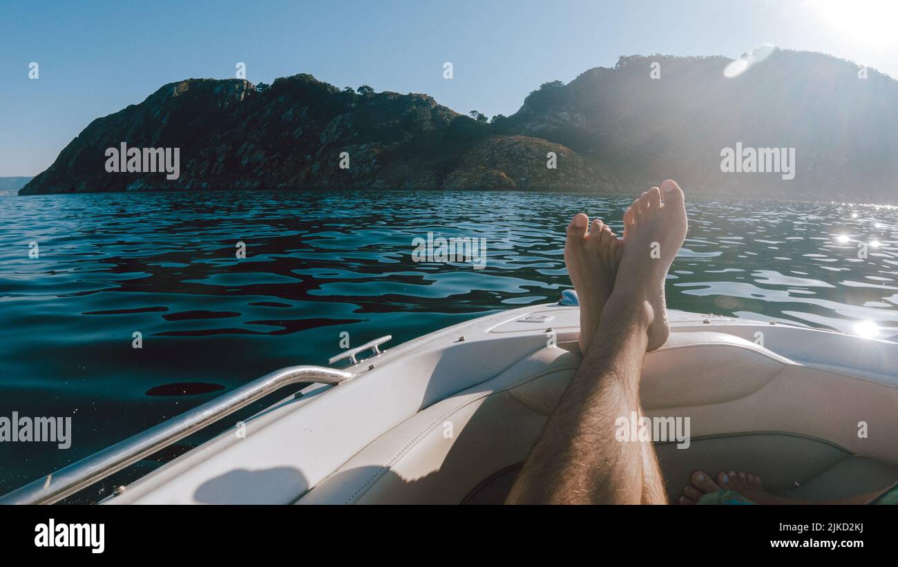 First person view of a man relaxing on a boat with his legs resting on ...