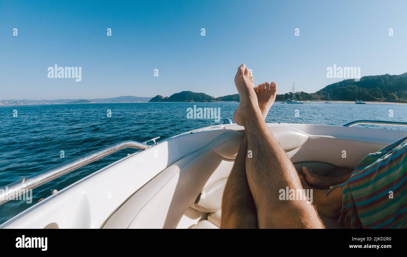 First person view of a man relaxing on a boat with his legs resting on ...
