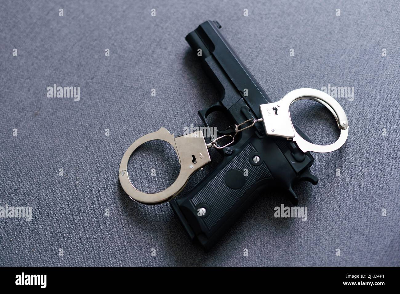 Gun with handcuffs over dark background Stock Photo - Alamy