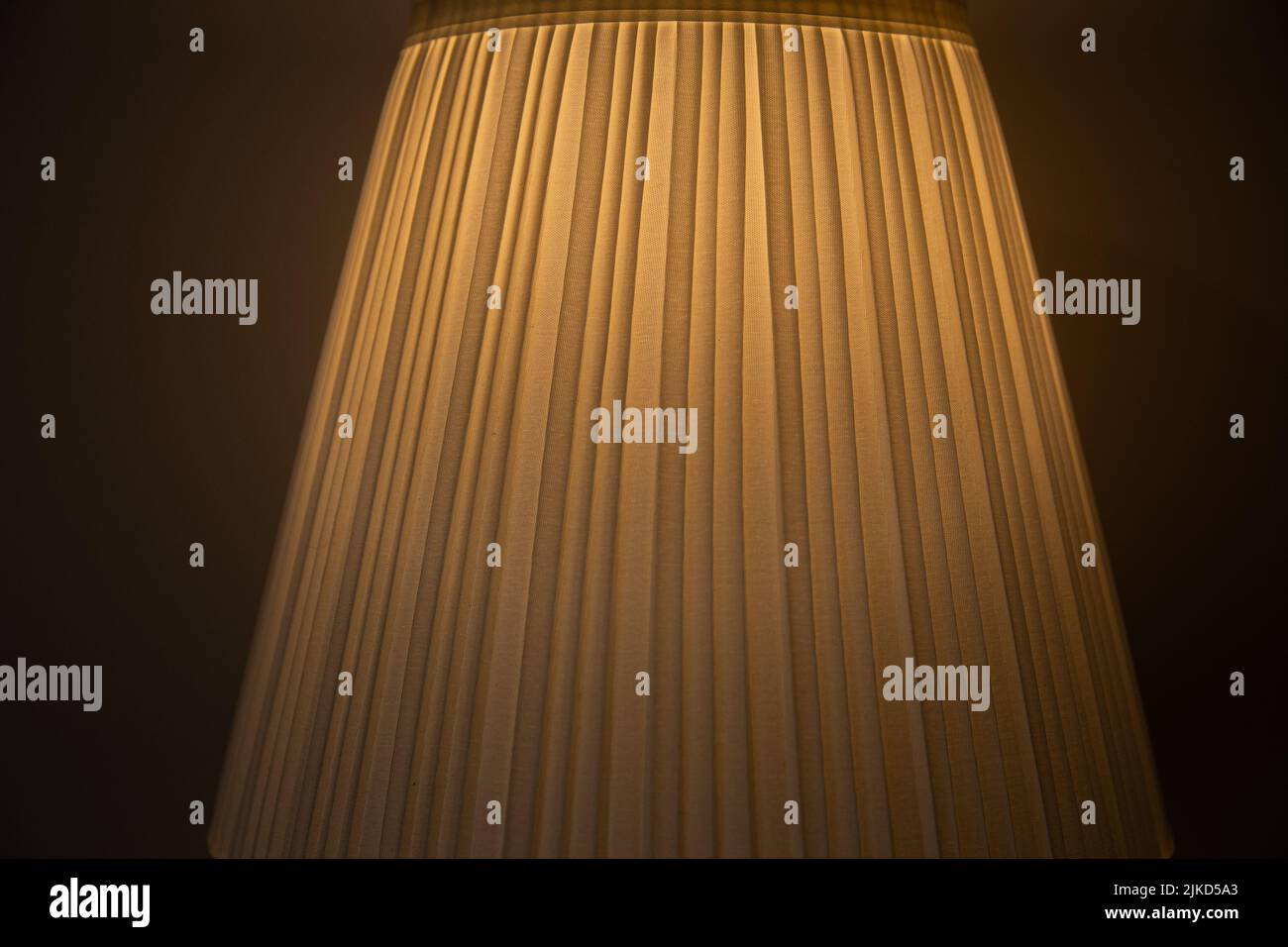 The fabric lampshade of the sconce is illuminated from the inside by ...