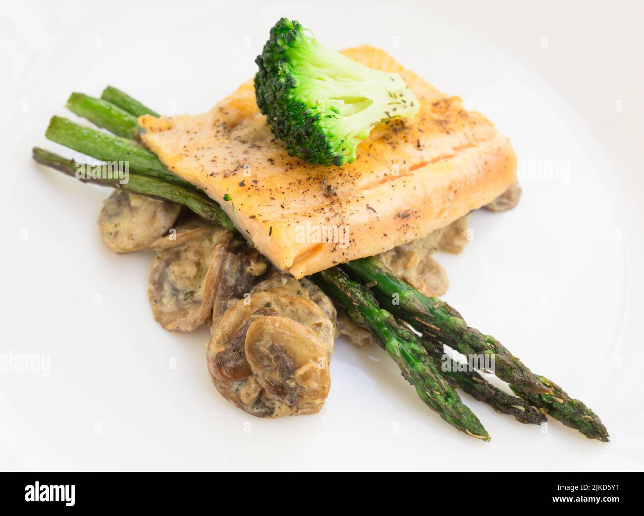 dish of fried river trout fillet with garnish of broccoli, asparagus ...
