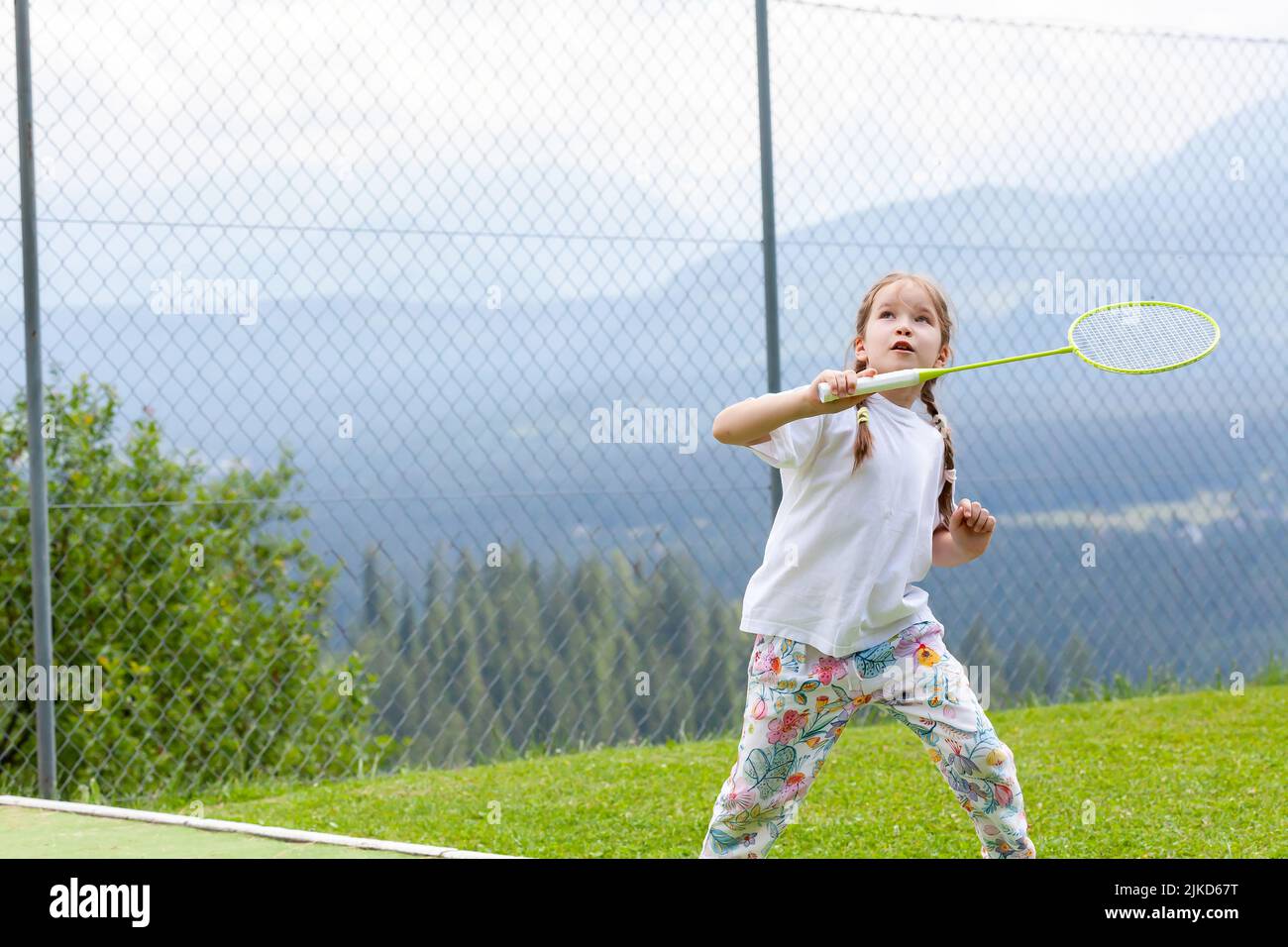 Happy sporty primary school age child, girl playing badminton outdoors ...