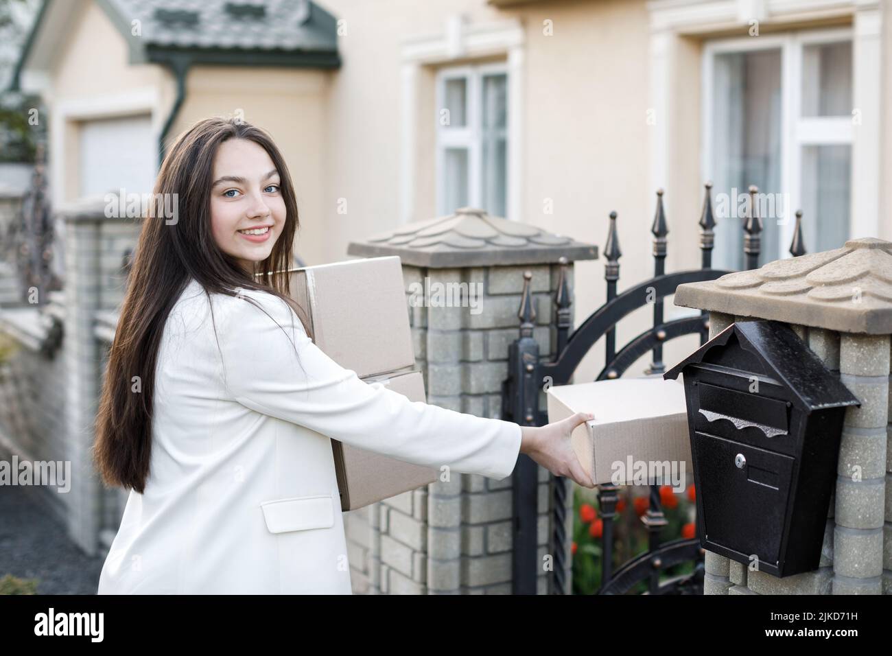 Young woman carrying parcels home, standing with a heap of cardboard ...