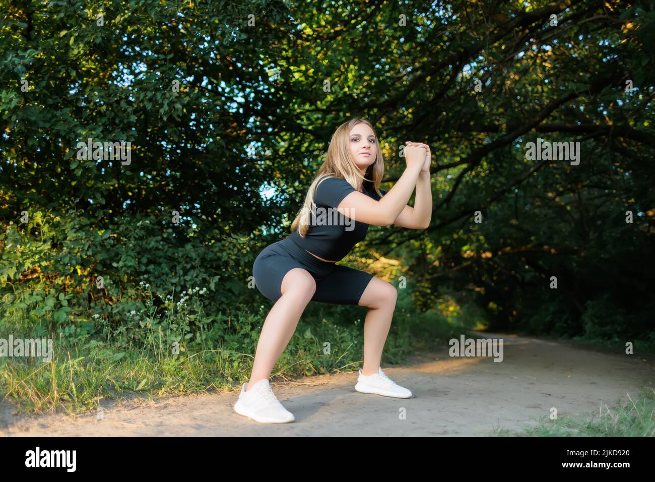 girl fitness model goes in for sports in the park doing squats Stock ...