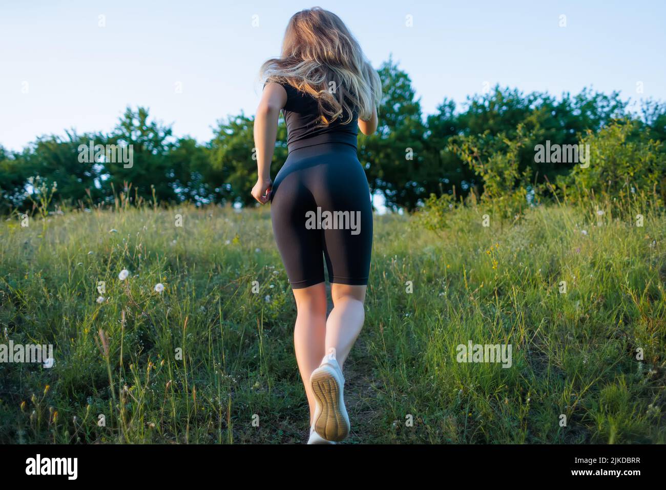 Fitness blonde running uphill, rear view Stock Photo - Alamy