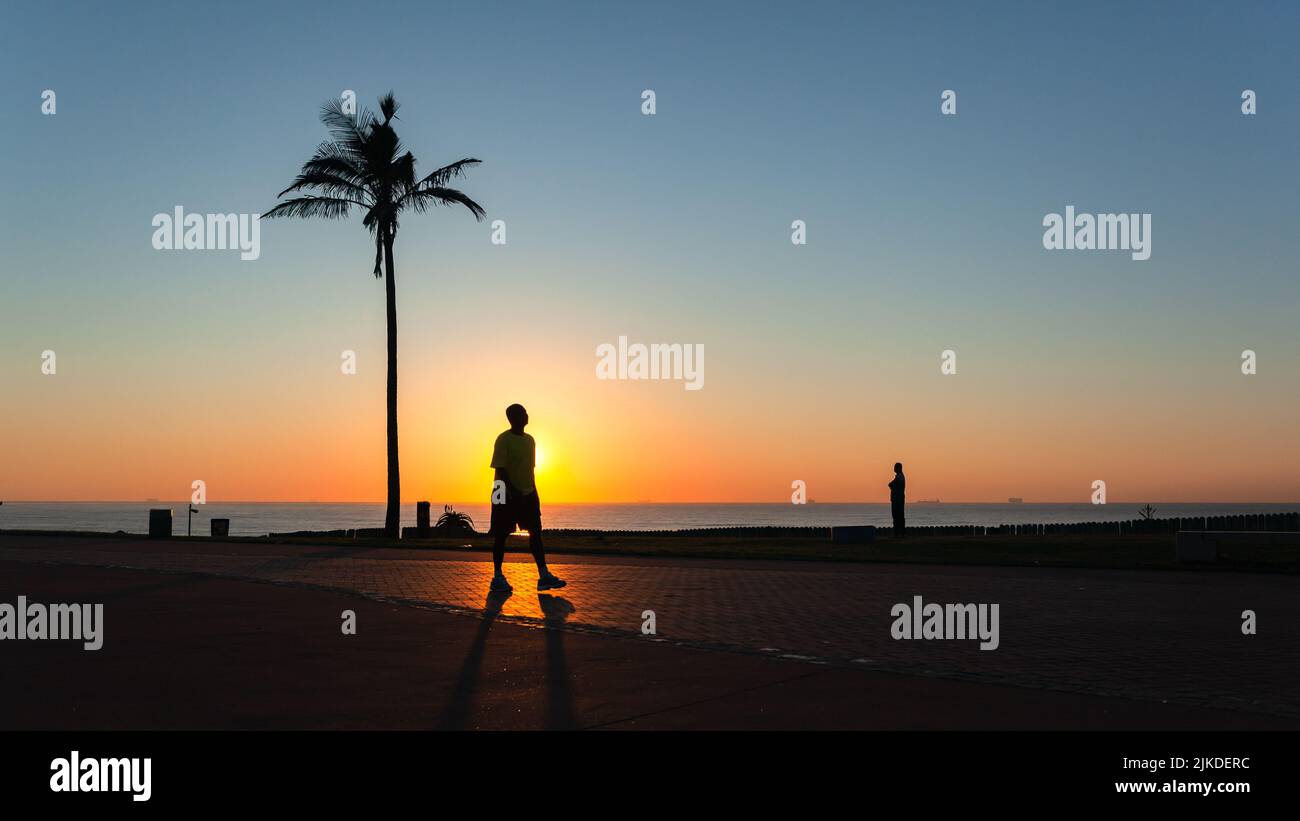 Dawn beach promenade path people silhouetted at sunrise from the ...