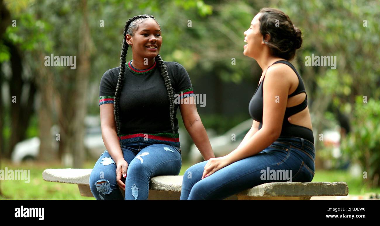 Two mixed race friends in conversation outdoors. Girlfriends speaking ...