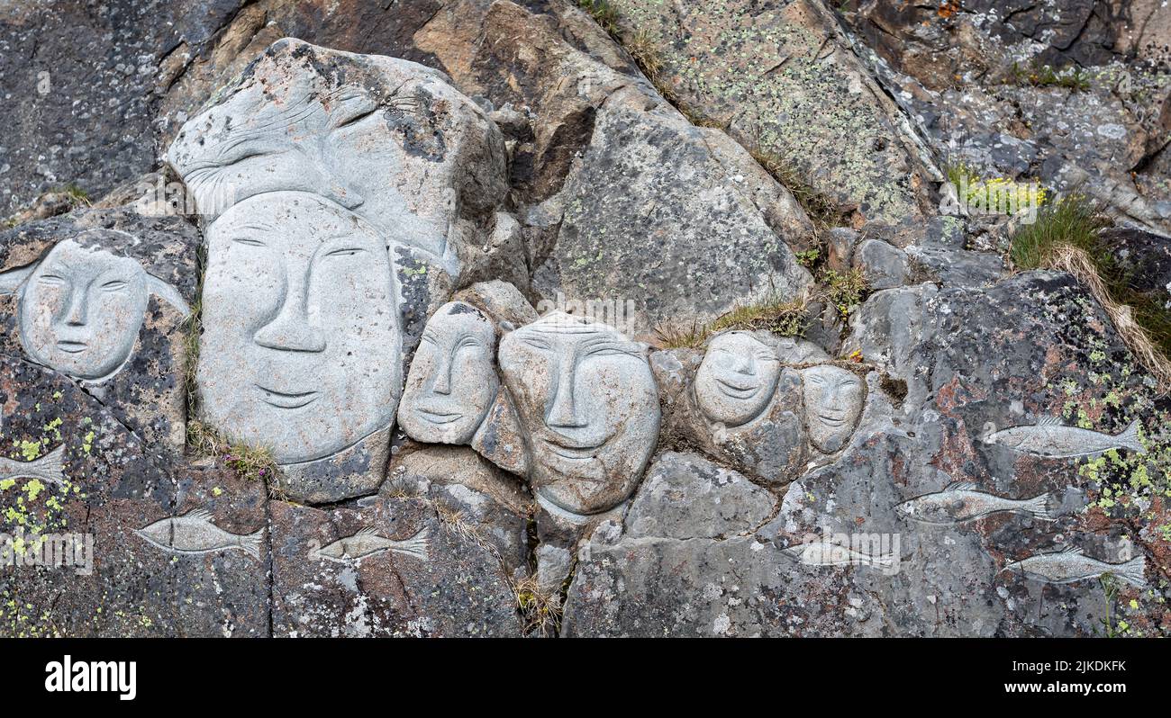 Smiling inuit faces and fish carved in rock face in Qaqortoq, Greenland ...