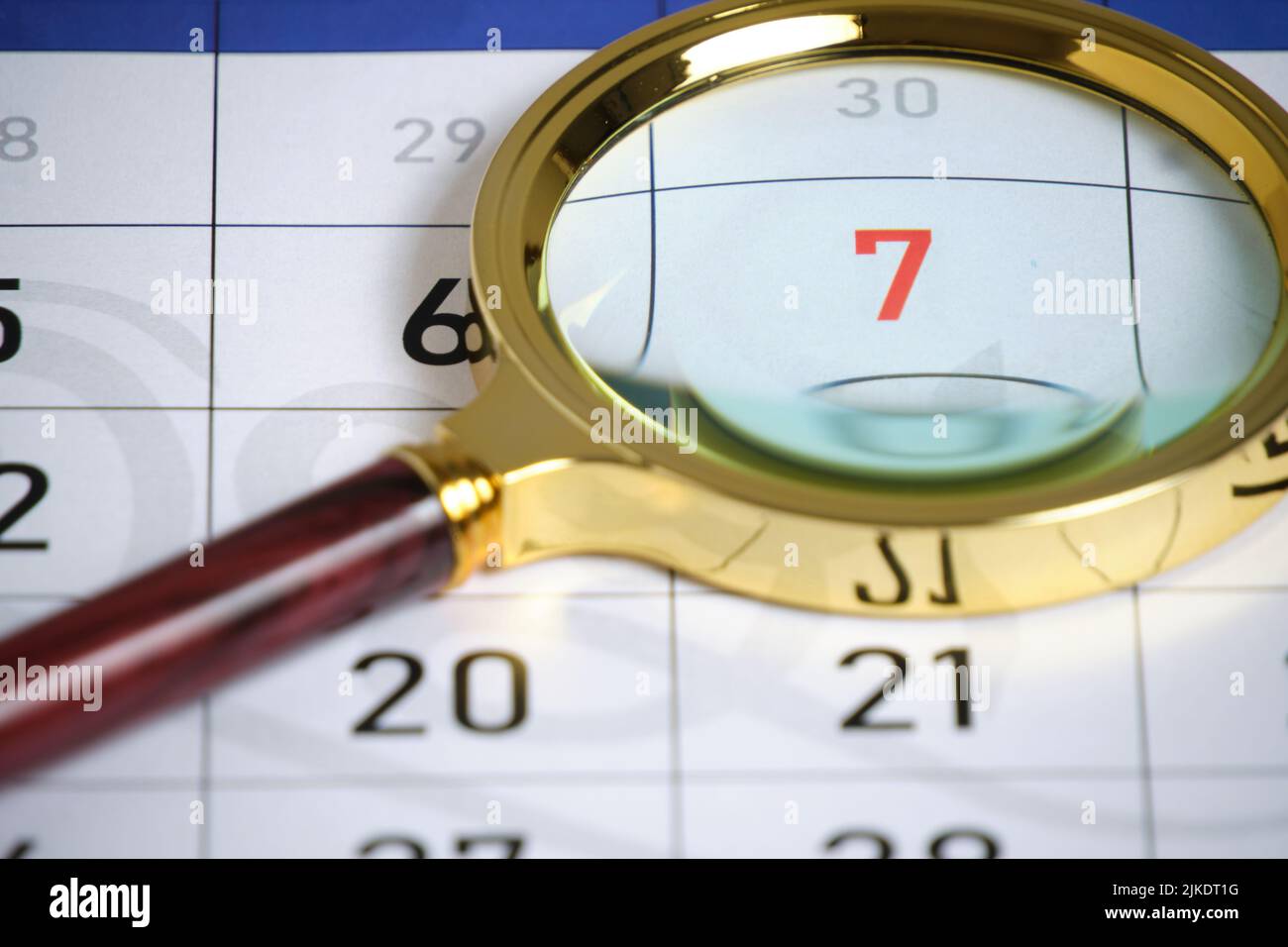 Calendar with number seven under magnifying glass Stock Photo - Alamy
