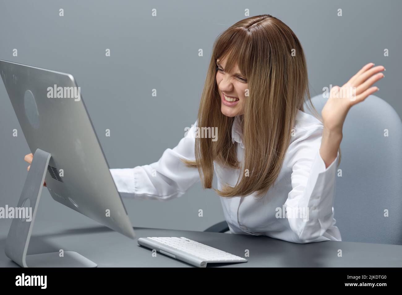 Angry evil pretty blonde businesswoman worker screaming to desktop ...