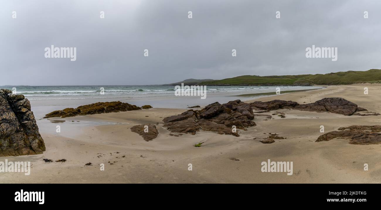 A beach panorama of Dog's Bay with large granite boulders and golden ...