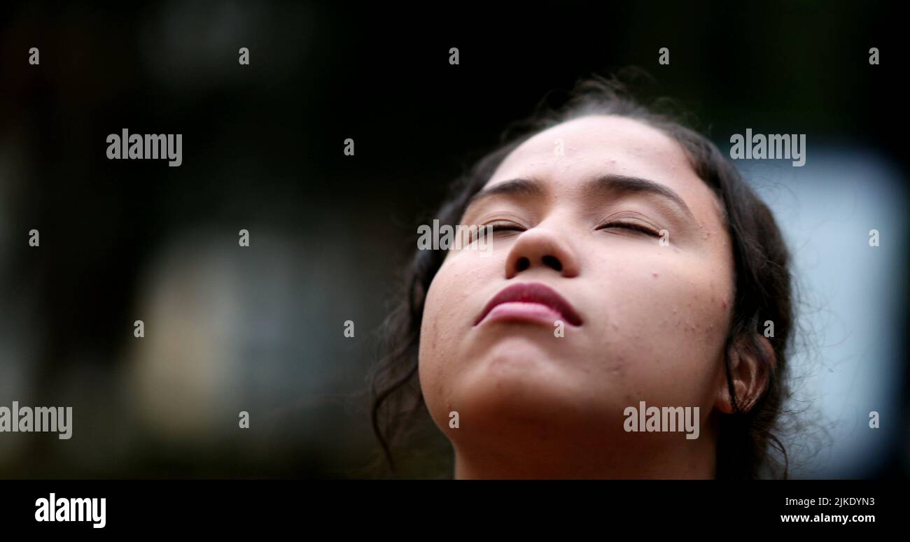Young woman opening eyes outside in nature feeling freedom. Contemplative girl opens eye close ...