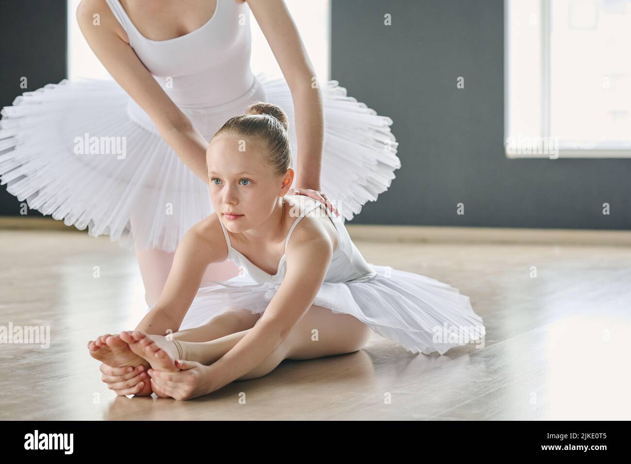 Cute youthful girl making effort while bending forwards over stretched ...