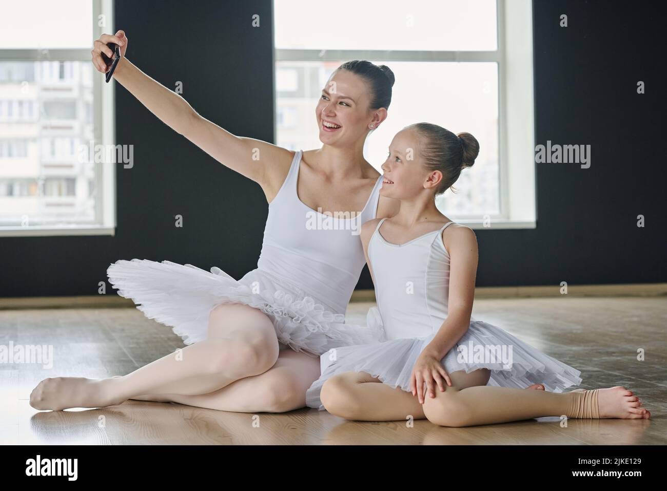 Cheerful young ballet teacher and her youthful learner making selfie on ...