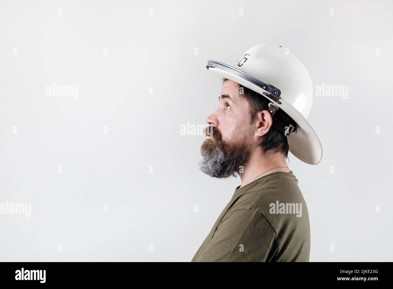 Bearded man in a fire helmet. Fireman portrait. Profile view. Copy ...