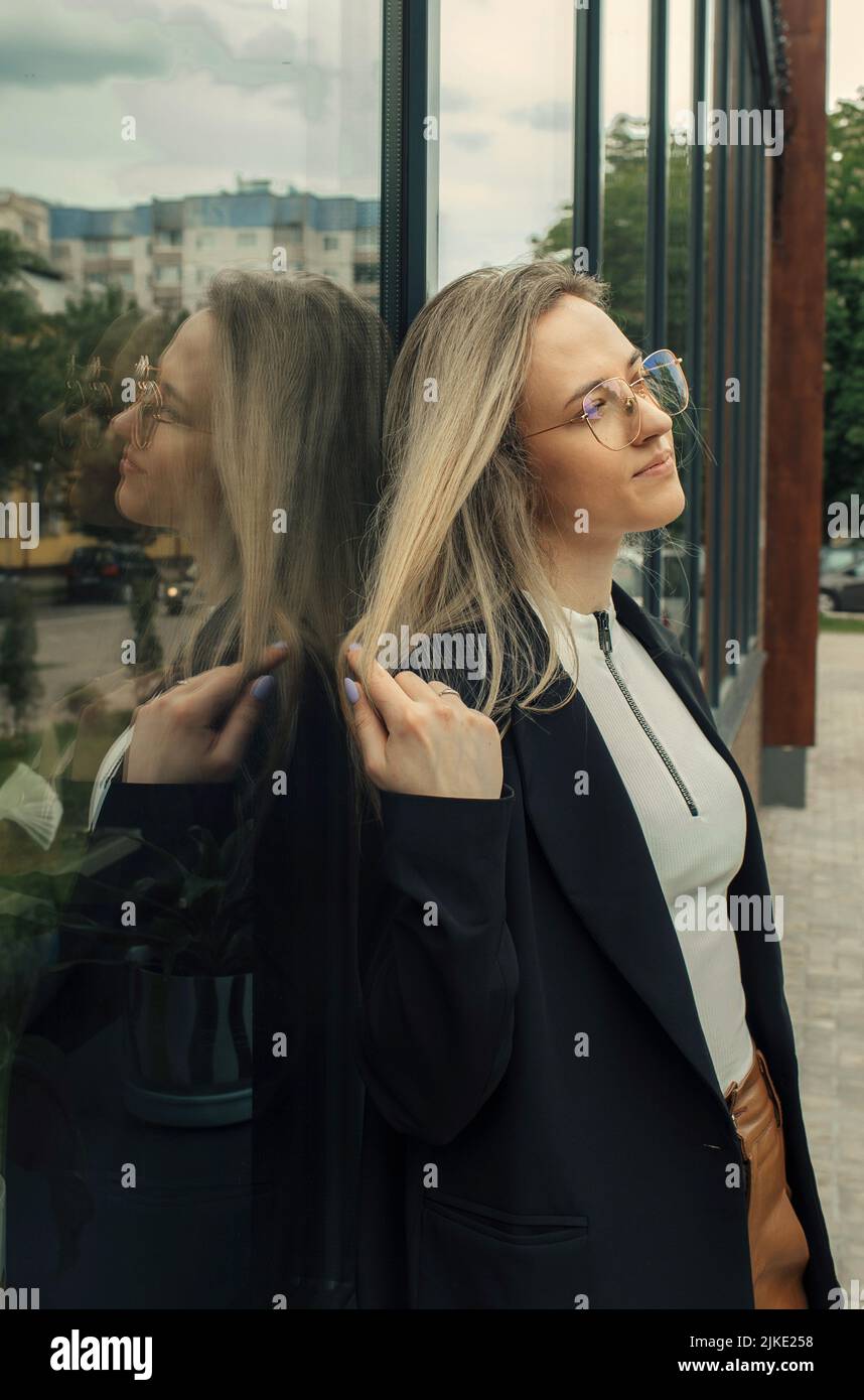 A beautiful woman stands leaning against the window of a building ...
