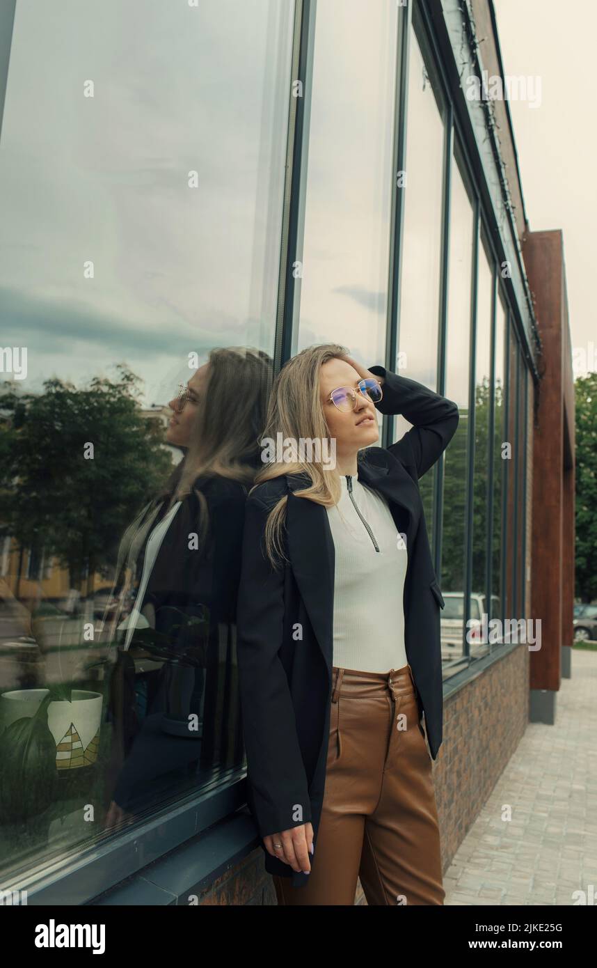 A beautiful woman stands leaning against the window of a building ...