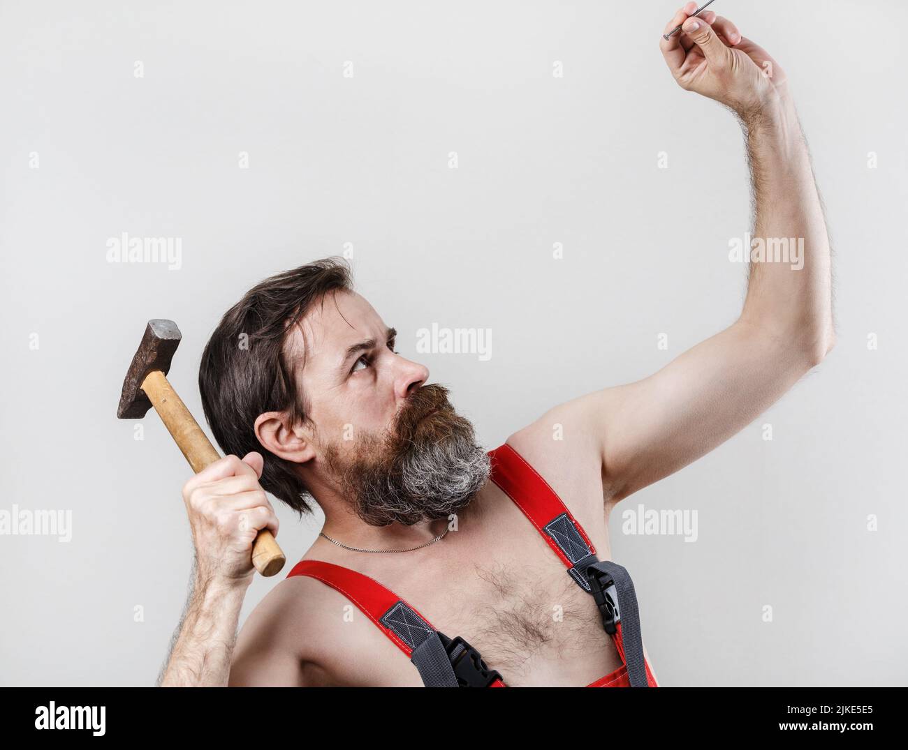 Worker hammers a nail with a hammer. Bearded man with hammer Stock ...