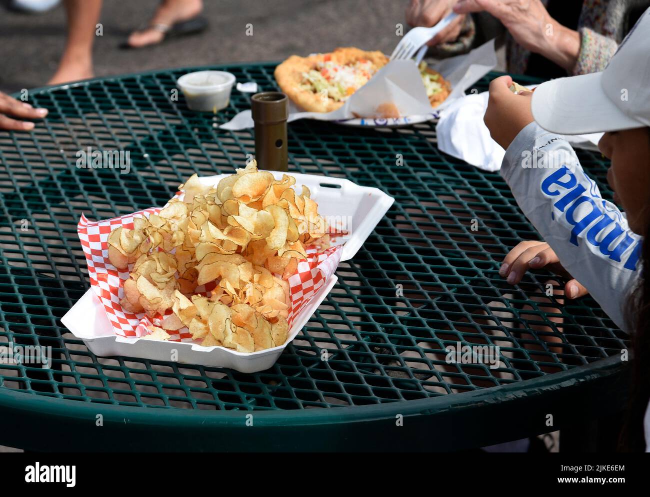 A family enjoys eating ribbon fries at an outdoor festival in Santa Fe ...