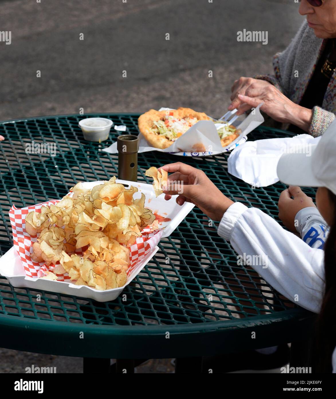 A family enjoys eating ribbon fries at an outdoor festival in Santa Fe ...